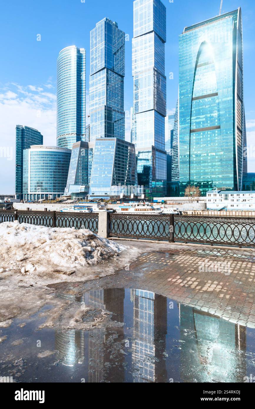 spring urban landscape with view of Moscow City and melting snow puddle ...