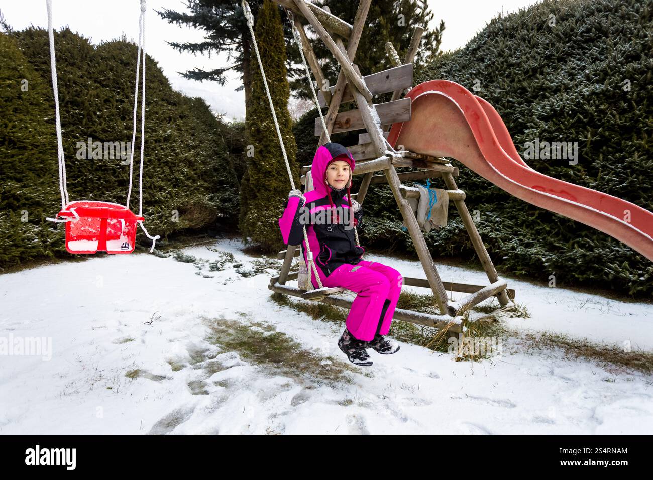 Cute little girl swinging on playground at cold snowy day Stock Photo ...