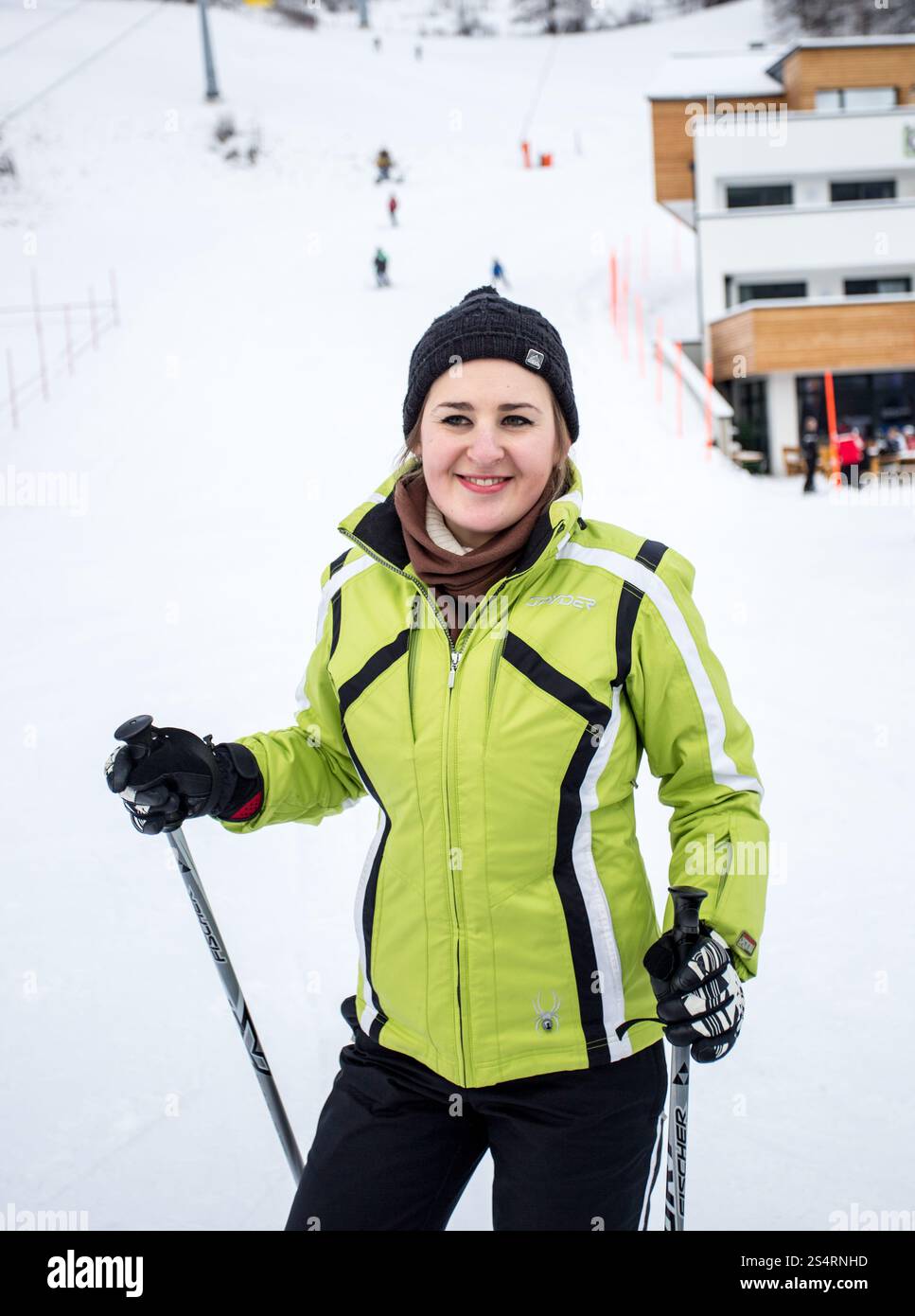 Closeup portrait of cute smiling female skier on downhill of ski slope ...