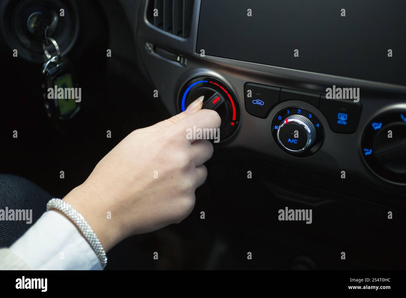 Female driver turning car air conditioner knob Stock Photo - Alamy