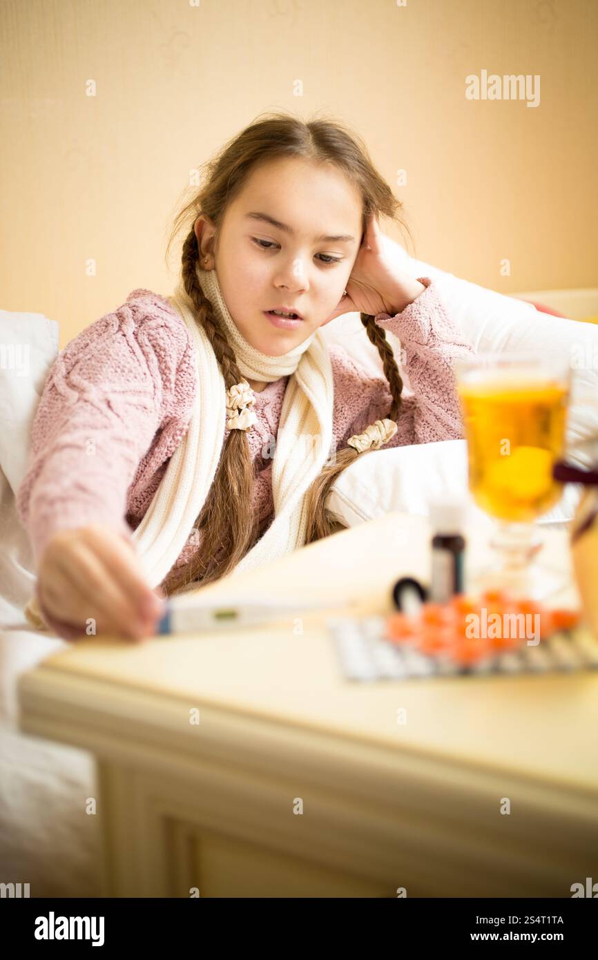 Closeup portrait of little sick girl lying in bed and looking at ...