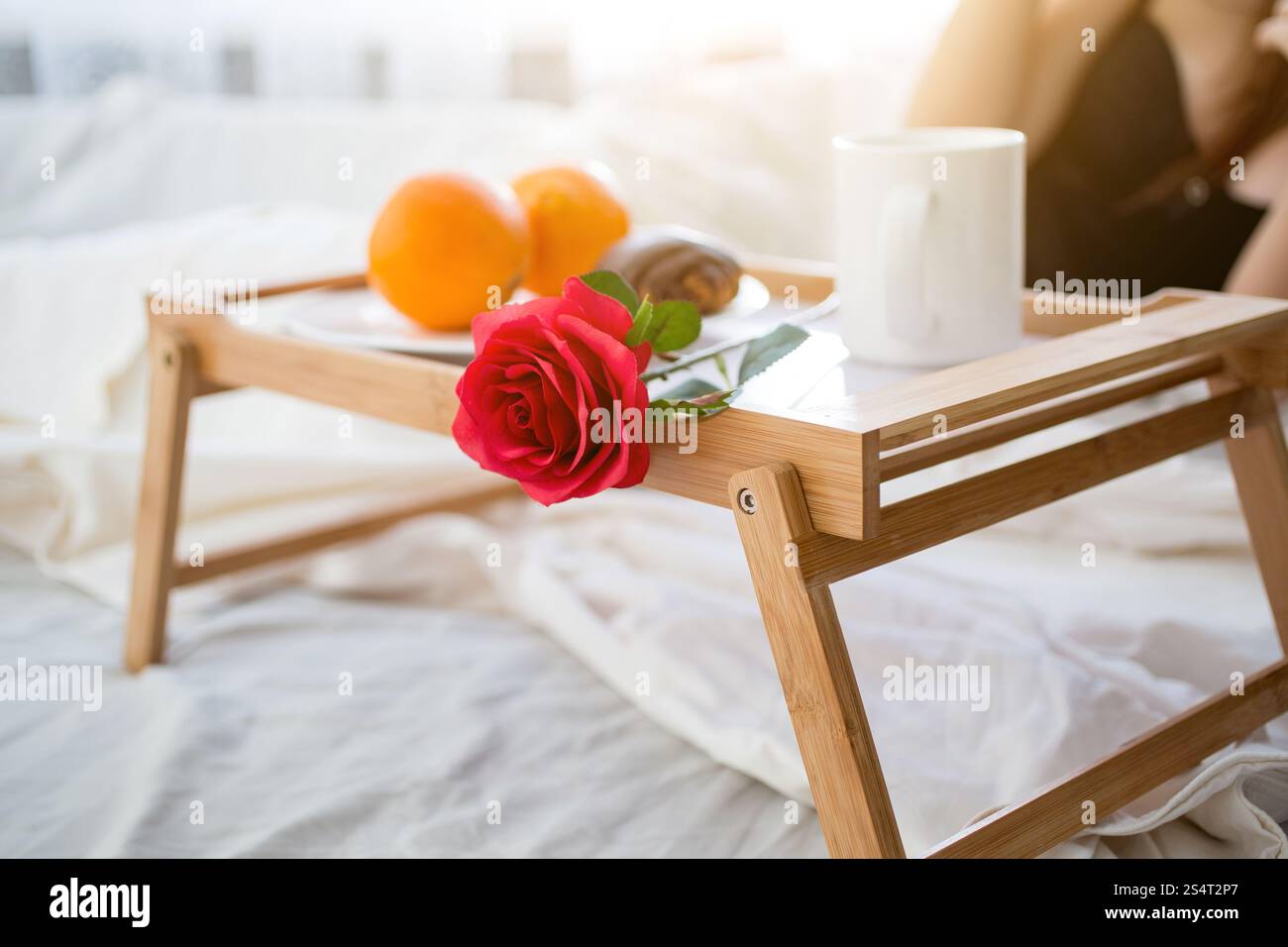 Closeup photo of tray with breakfast and red rose on bed at hotel room ...