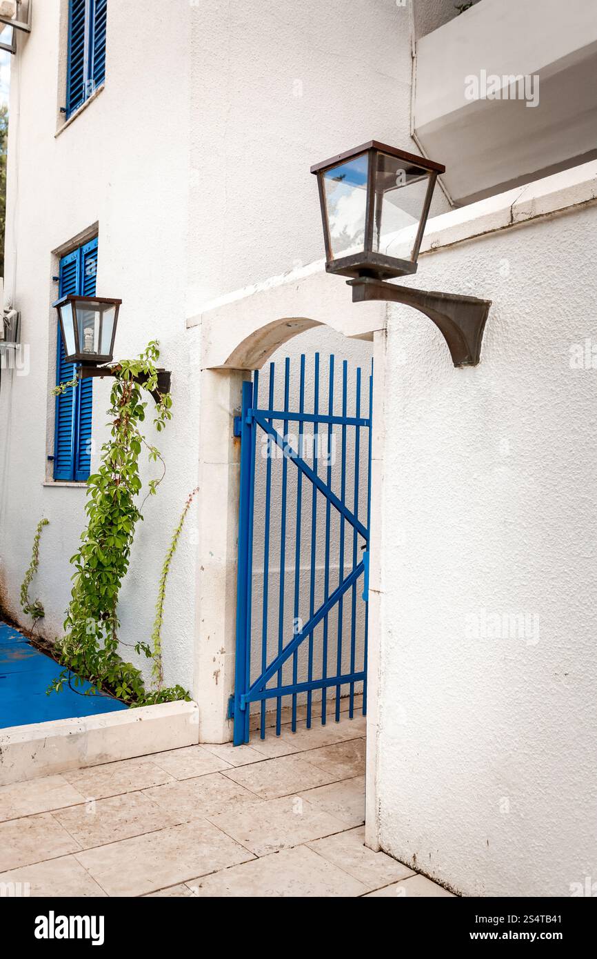 Painted blue gates in white wall with gas lamp at greek style Stock ...
