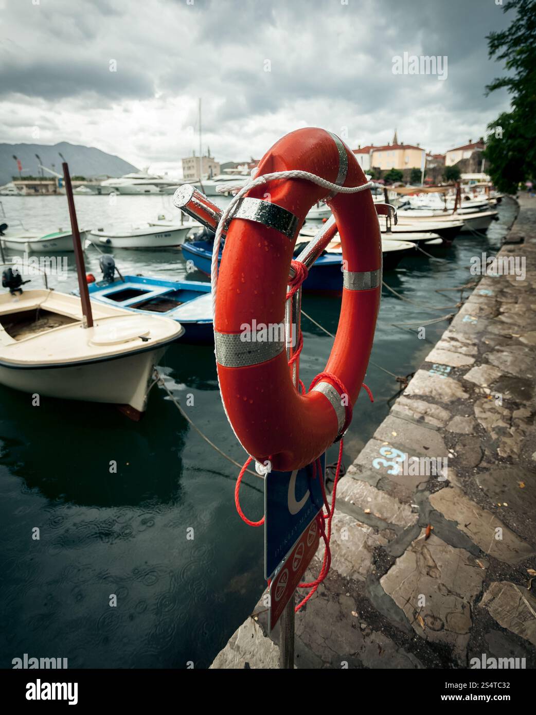 Red lifebuoy hanging in sea port at rainy day Stock Photo - Alamy
