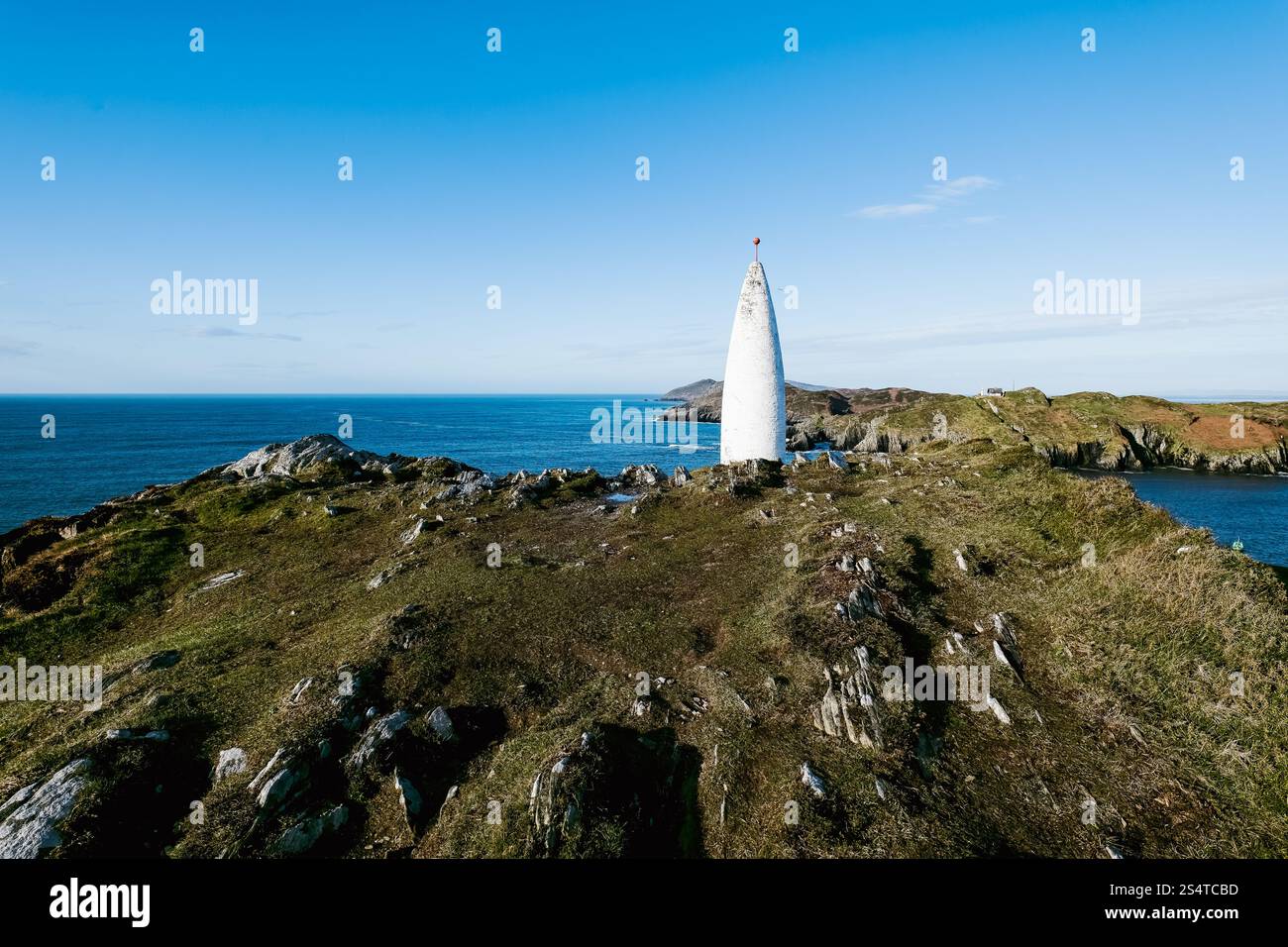 Coastal scene. A white, conical landmark stands on a rocky outcrop ...