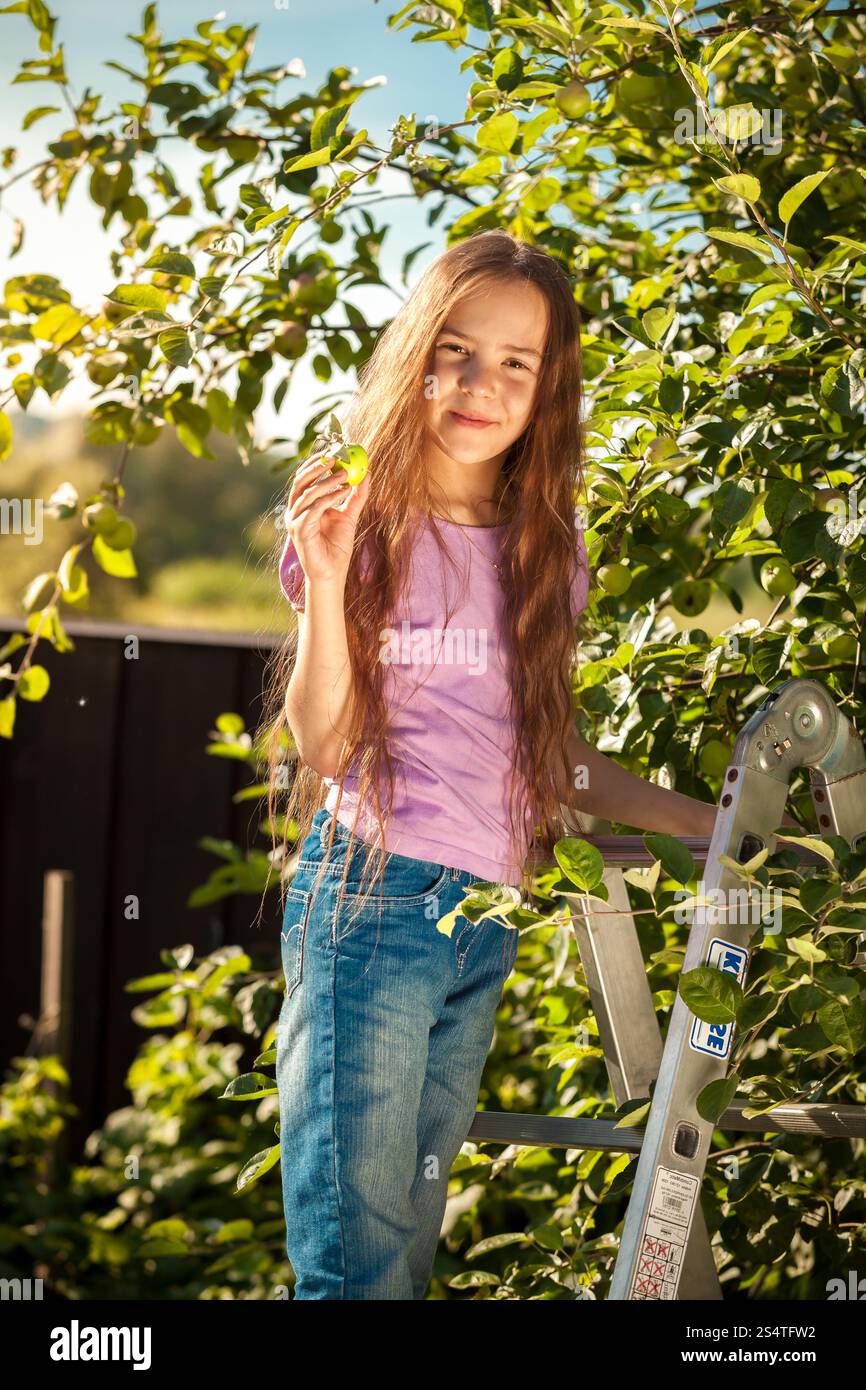 Beautiful smiling girl standing on ladder at garden Stock Photo - Alamy