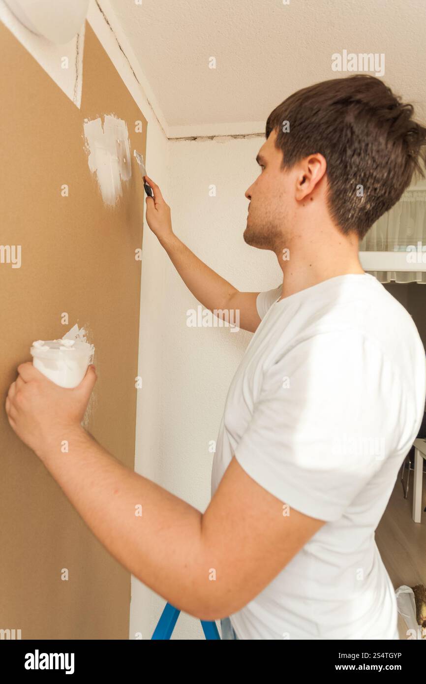 Closeup portrait of young man aligning wall with putty Stock Photo - Alamy