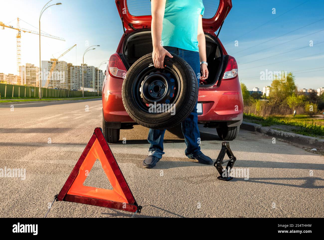 Photo of man holding spare wheel against broken car Stock Photo - Alamy