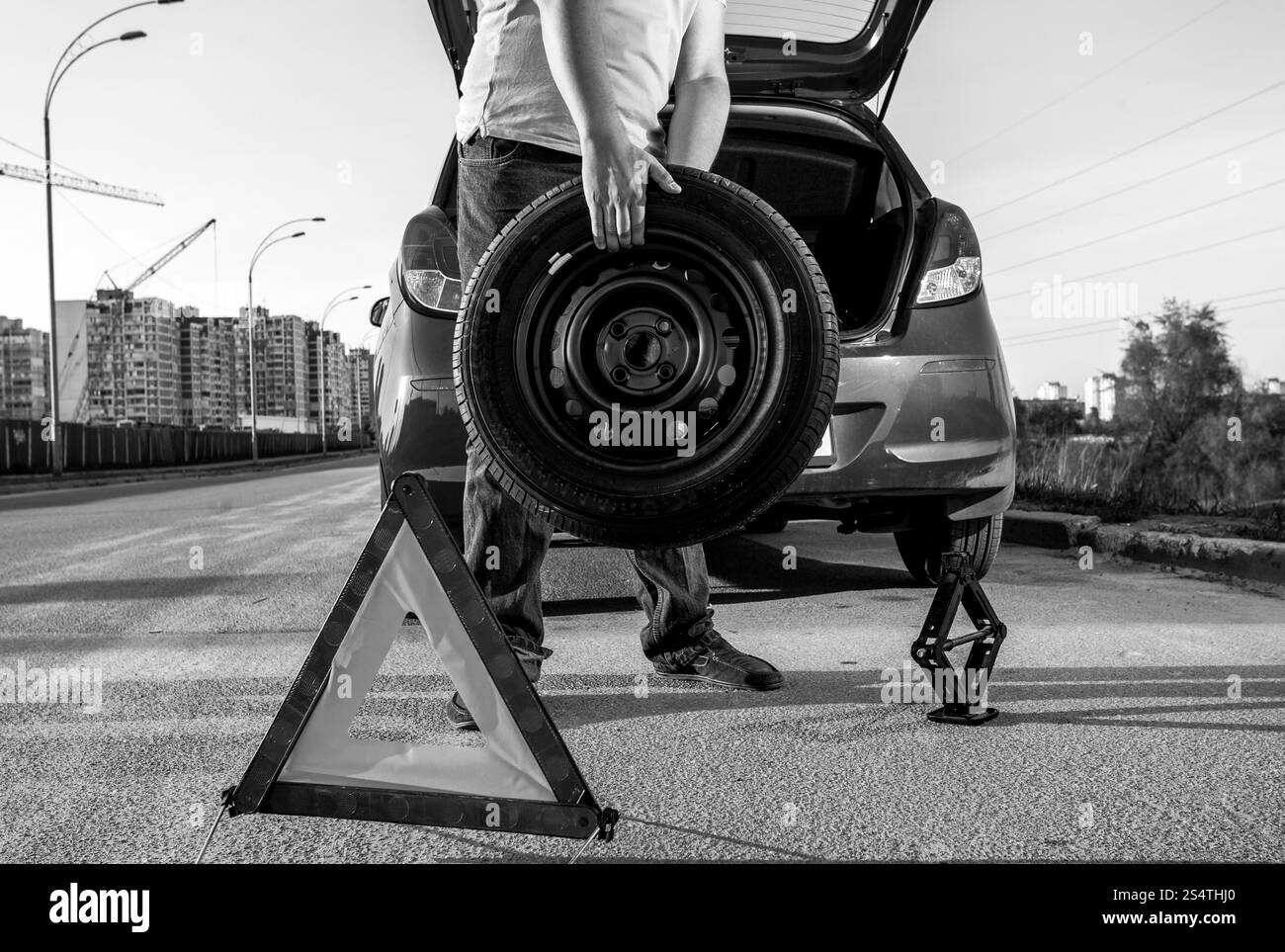Black and white closeup photo of man carrying spare wheel against ...