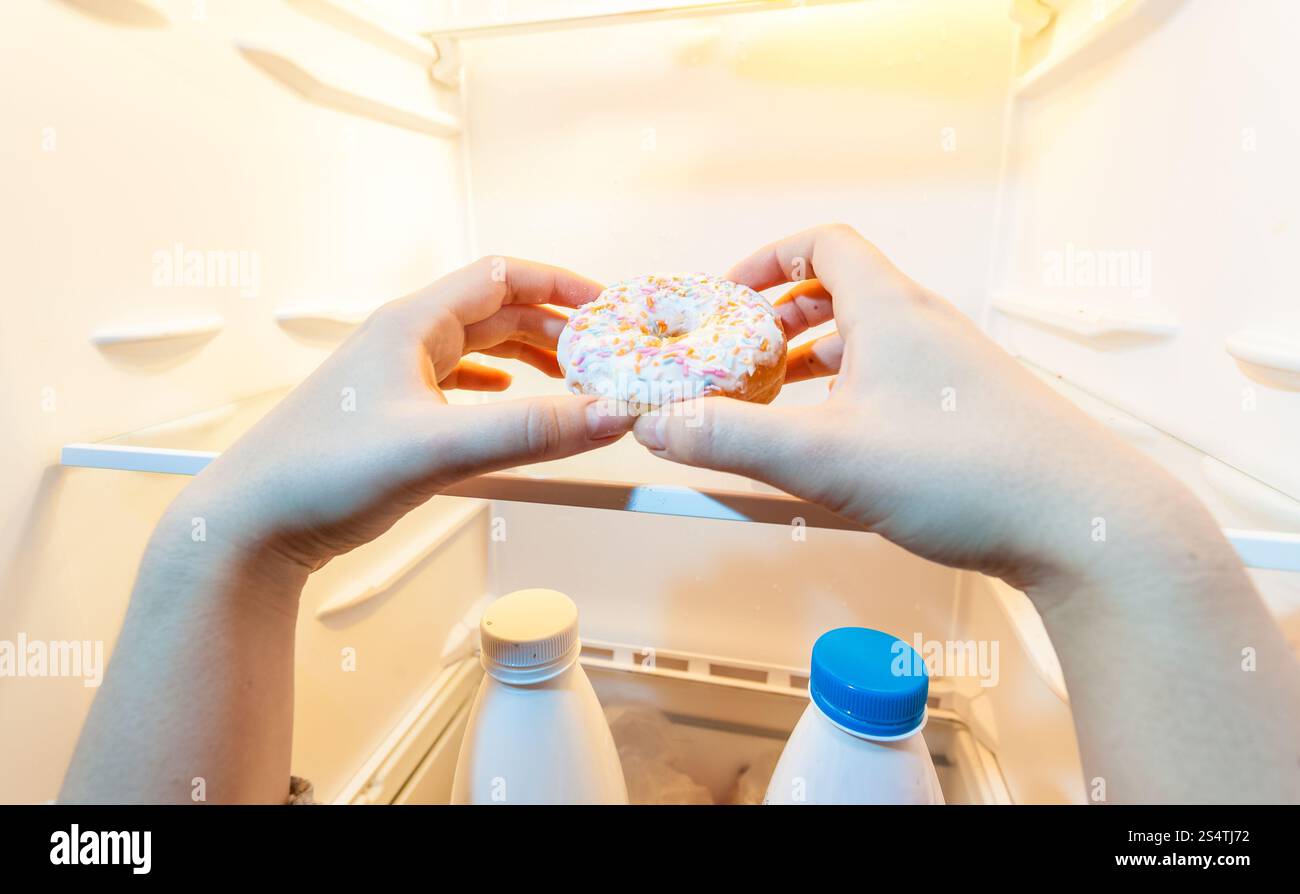 Closeup photo of female hand taking donut from refrigerator Stock Photo ...