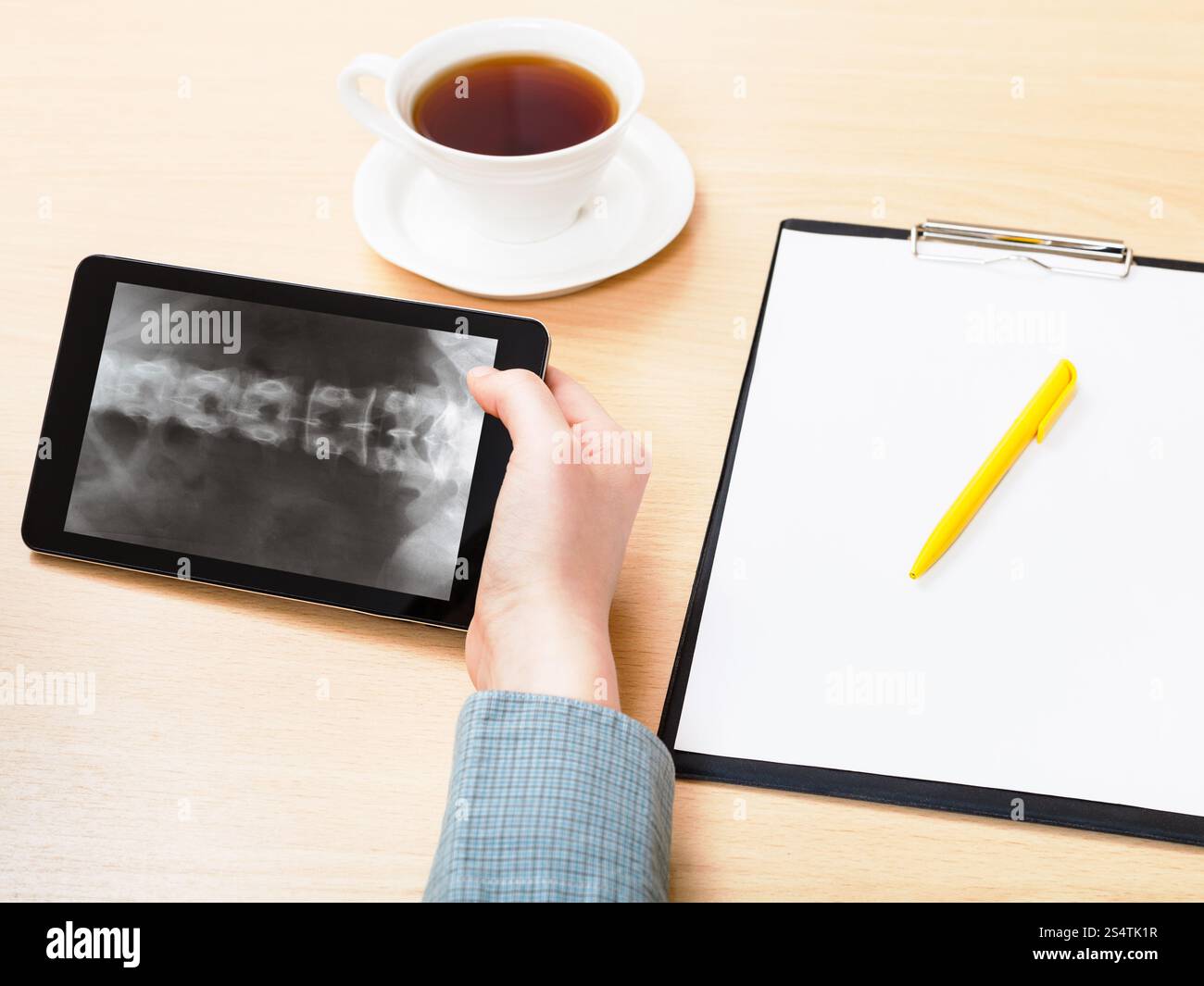 medic analyzes X-ray picture of vertebral column on screen on tablet pc ...