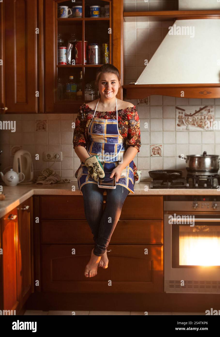 Beautiful woman sitting on tabletop while cooking dinner in oven Stock ...
