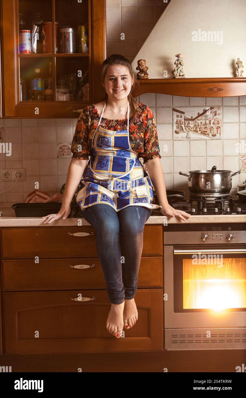 Beautiful smiling woman sitting on tabletop while baking in oven Stock ...