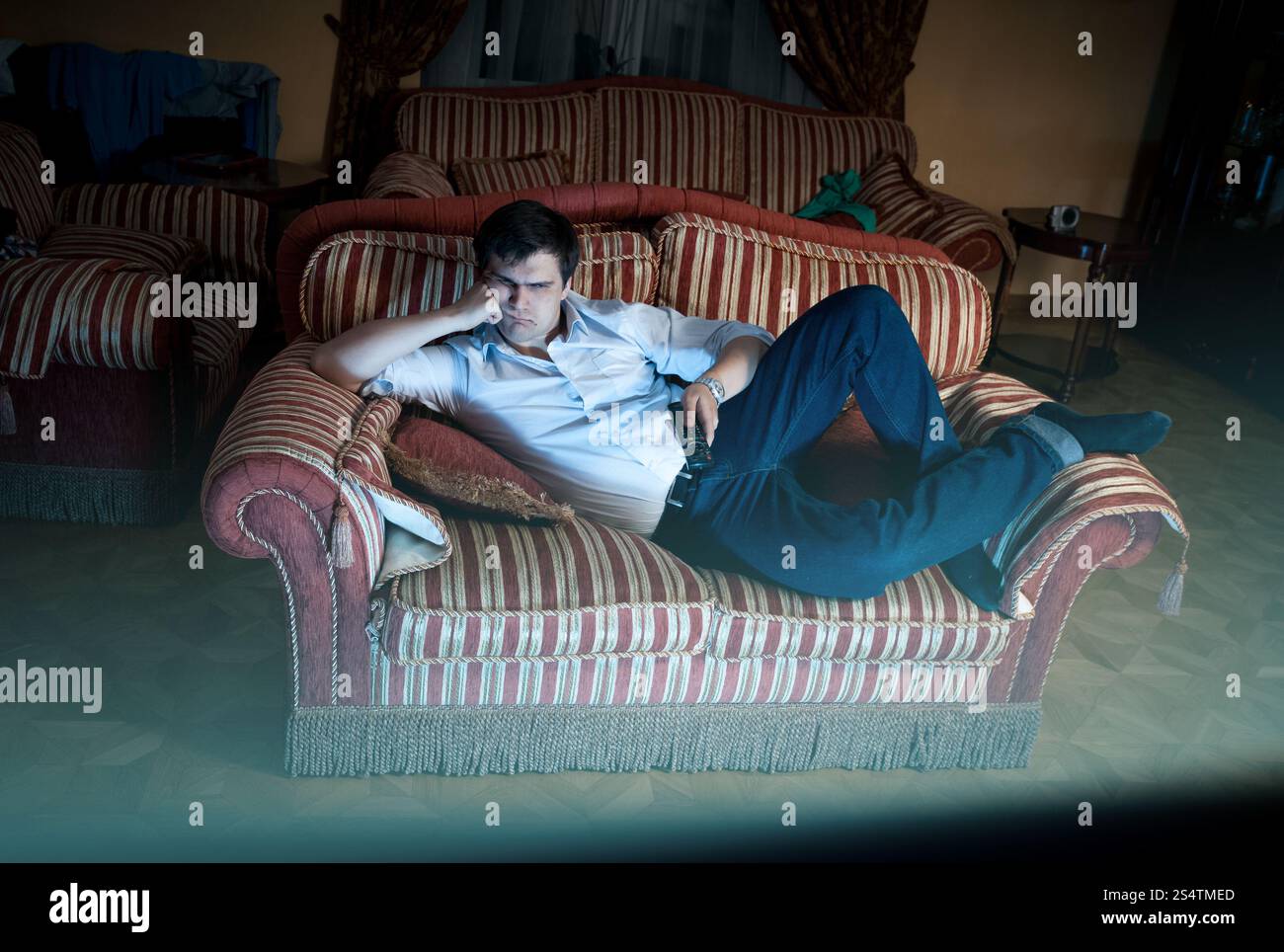 Young man lying on sofa and watching TV at night Stock Photo - Alamy