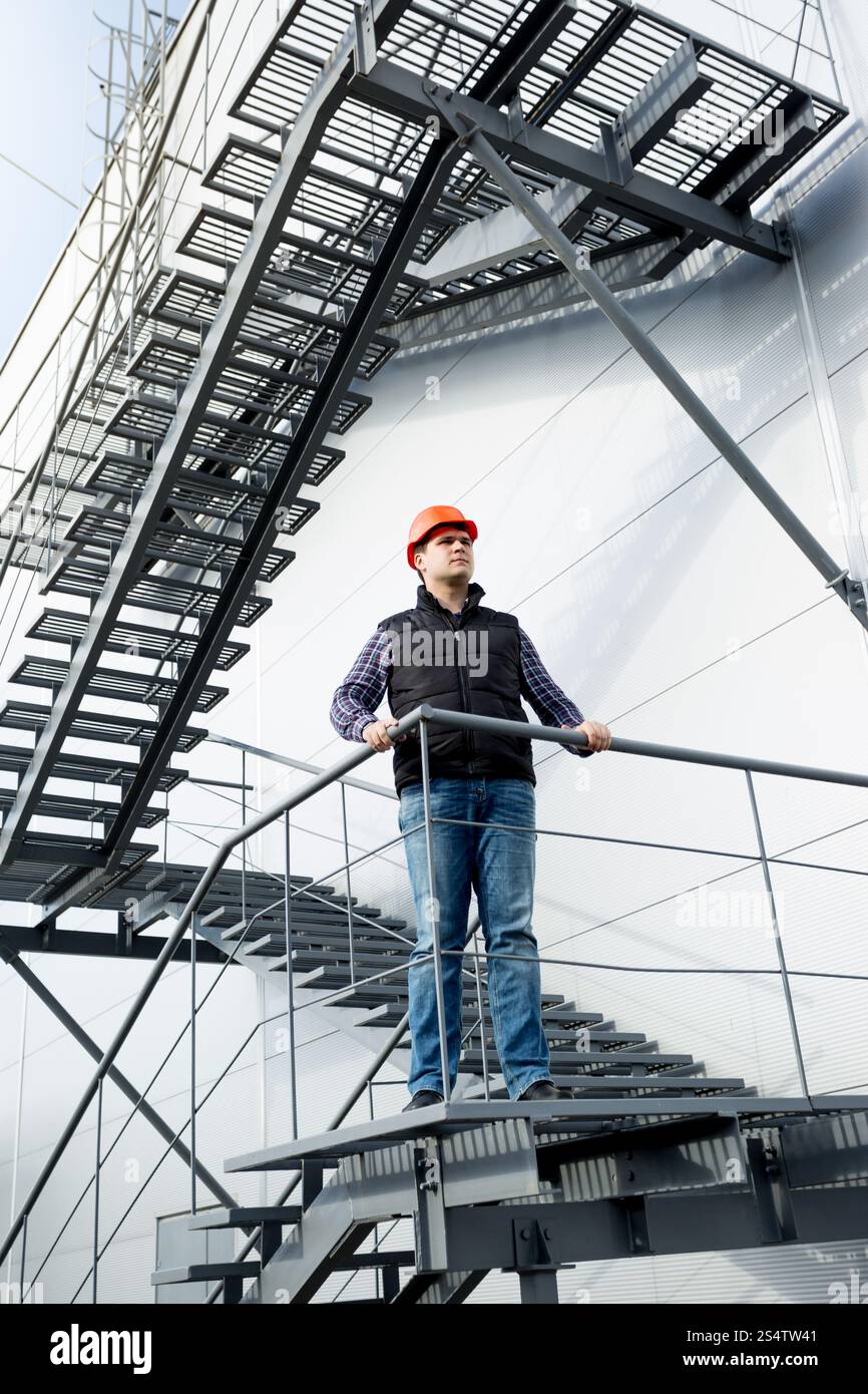 Male construction worker standing on steel staircase at factory Stock ...