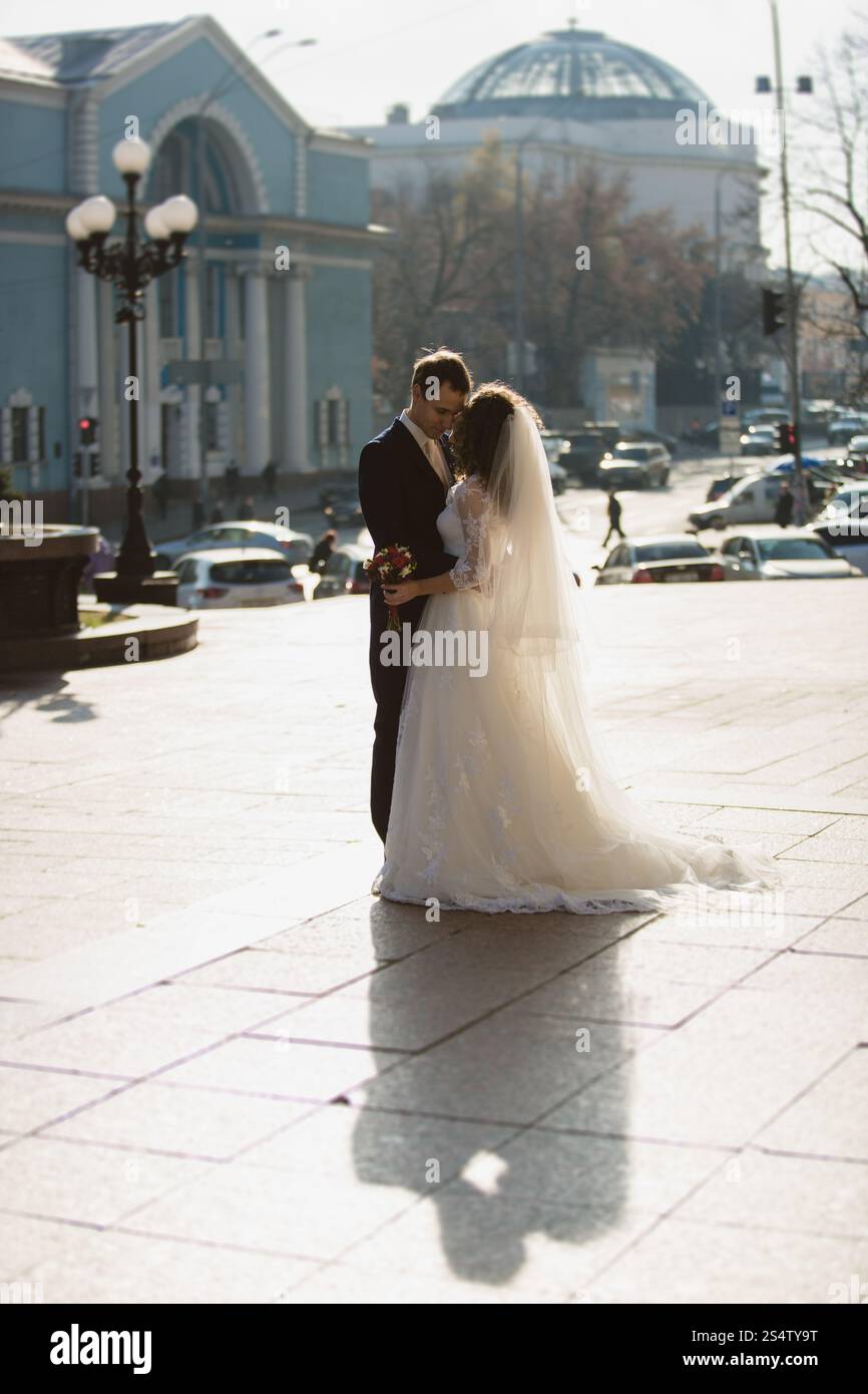 Toned photo of embracing just married couple on street at cold sunny ...