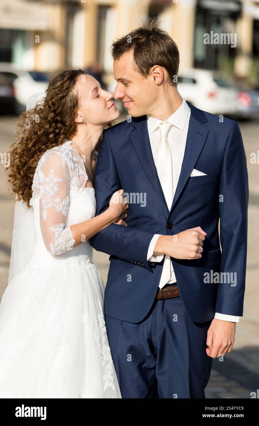Portrait of happy bride and groom holding hands and looking at each ...