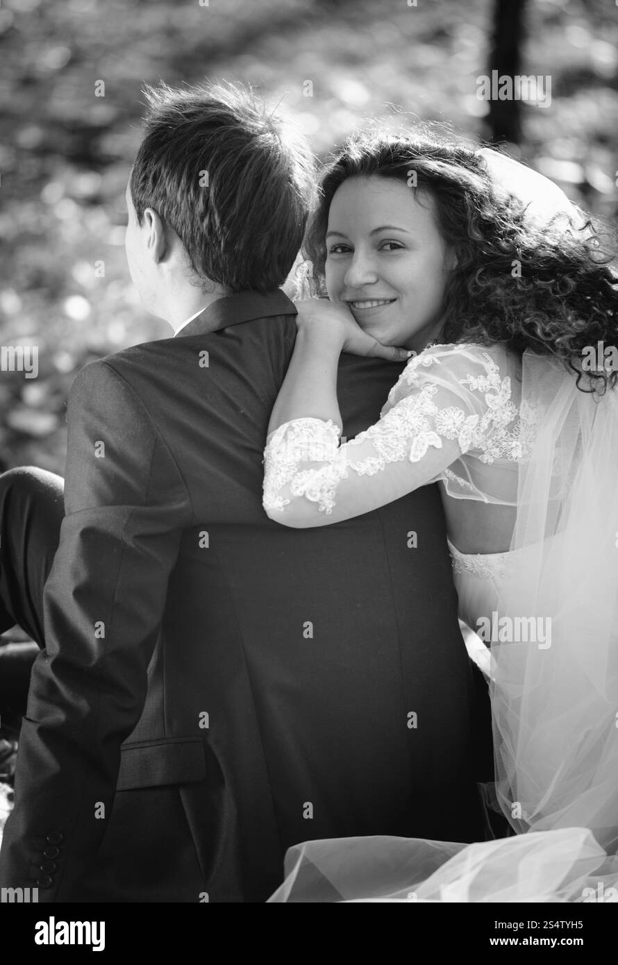 Black and white portrait of cute smiling bride hugging grooms back ...