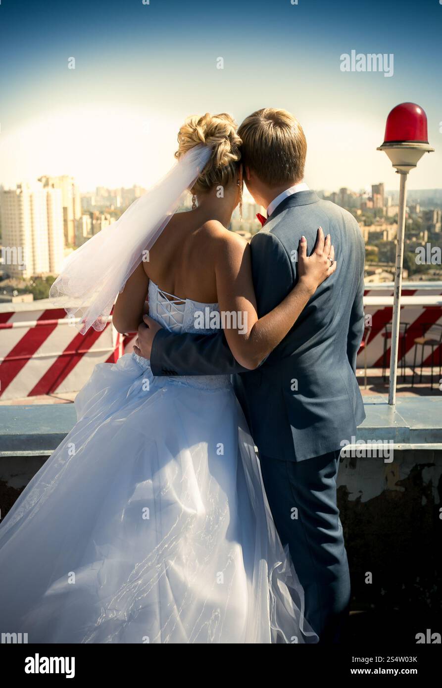 Just married couple standing on the roof top and looking at big urban ...