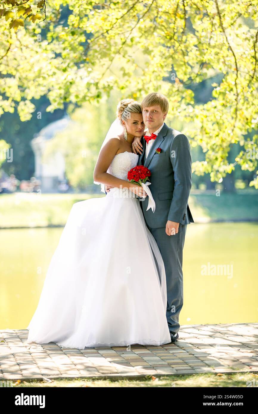 Happy newly married couple embracing at river under big tree Stock ...