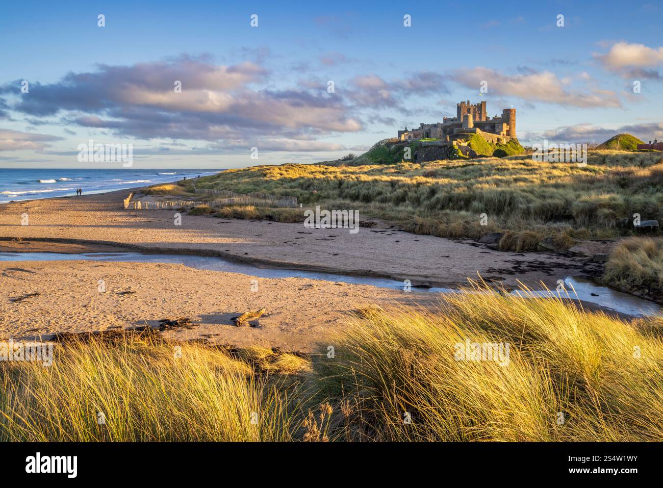 Bamburgh castle with Mill Burn flowing onto the beach, Northumberland ...