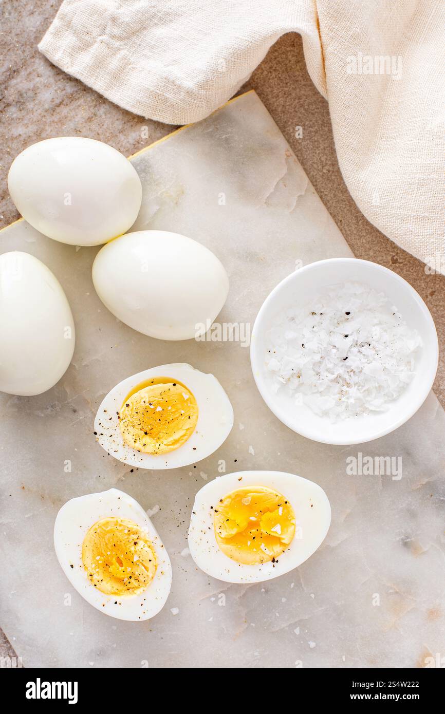 Soft boiled eggs cut in half with salt and black pepper Stock Photo - Alamy
