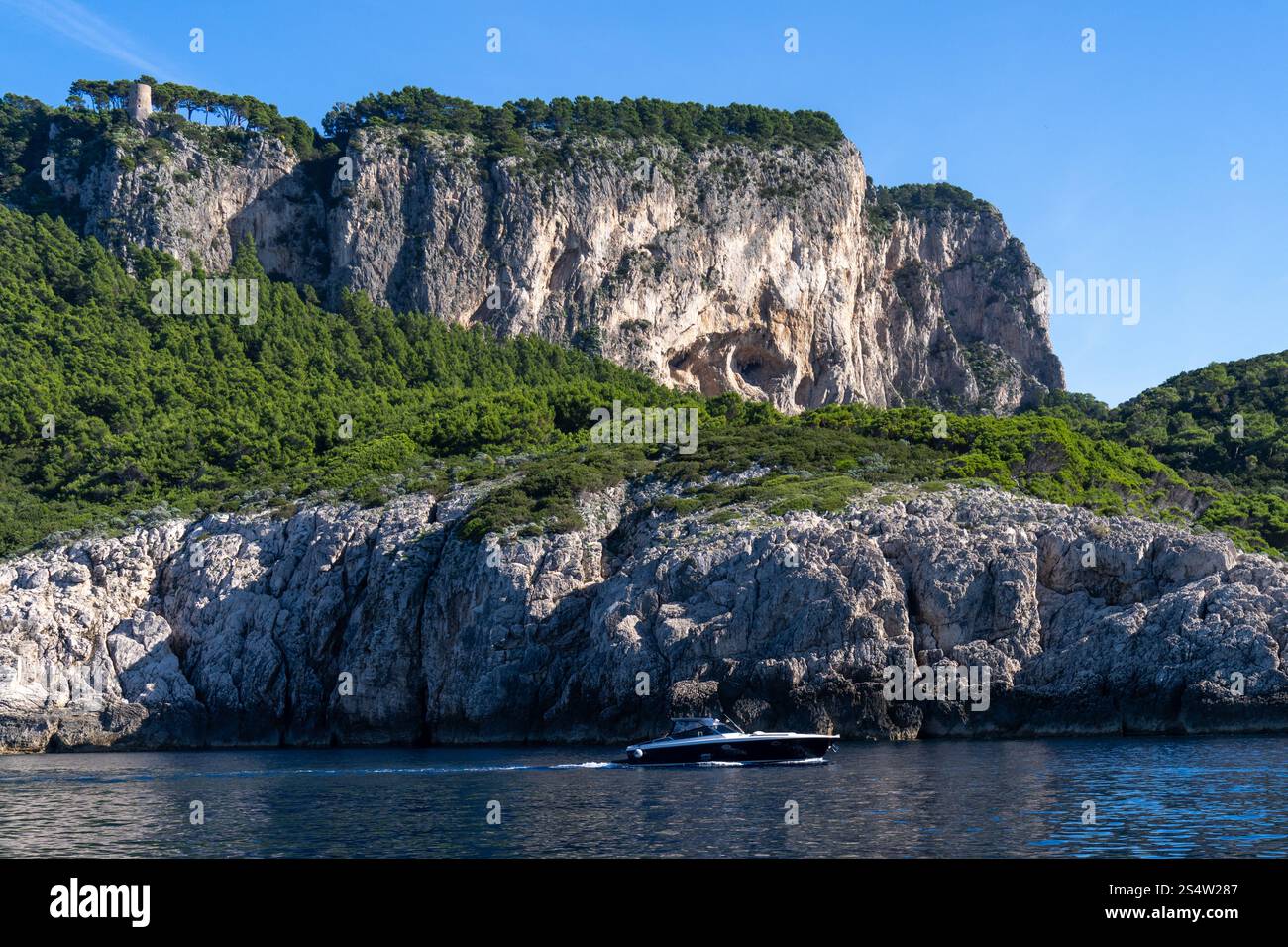 A powerboat passes beneath an old watchtower on the cliffs on the west ...