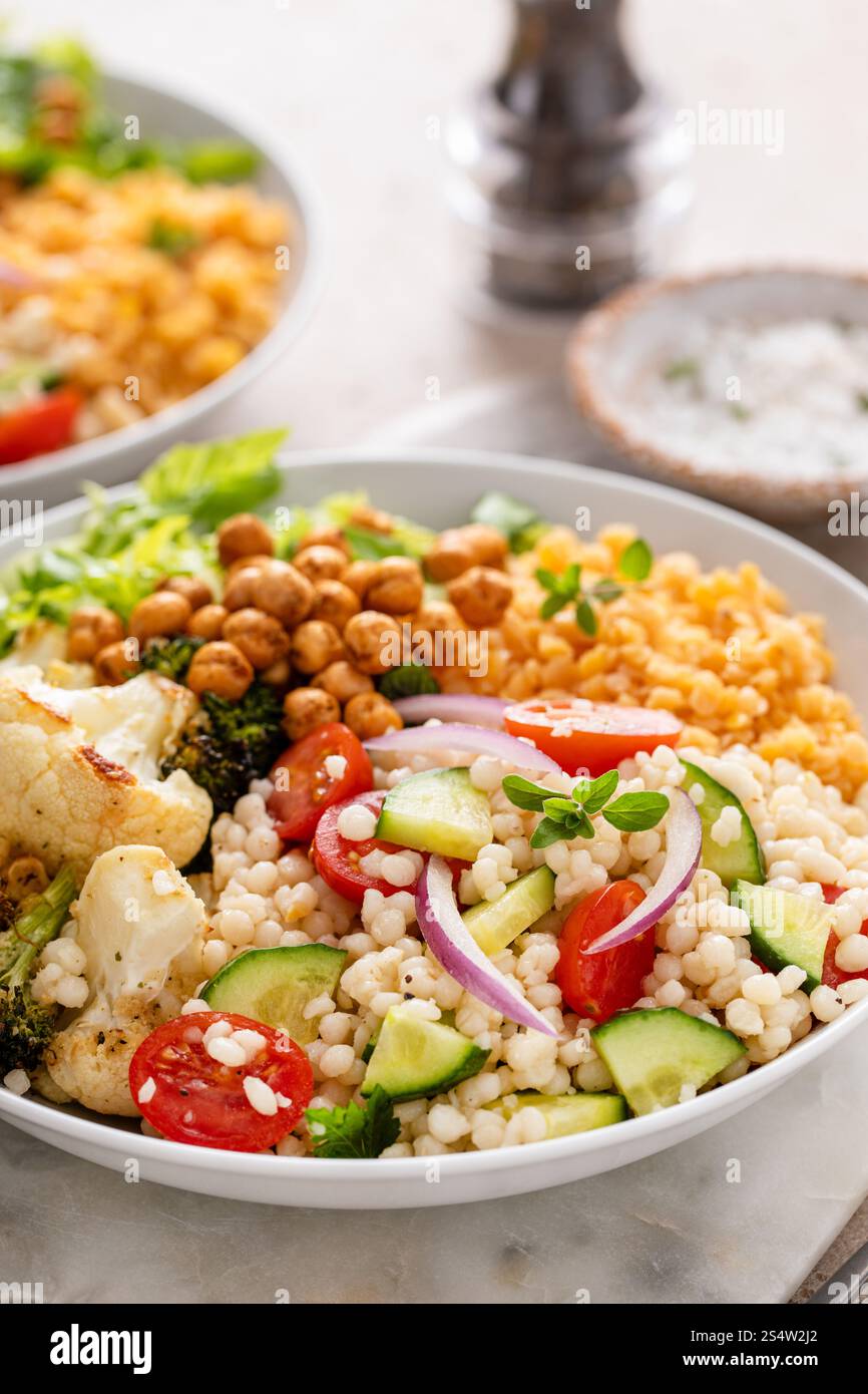 Vegan lunch bowl with lentils, roasted vegetables and chickpeas, pearl couscous salad with ...