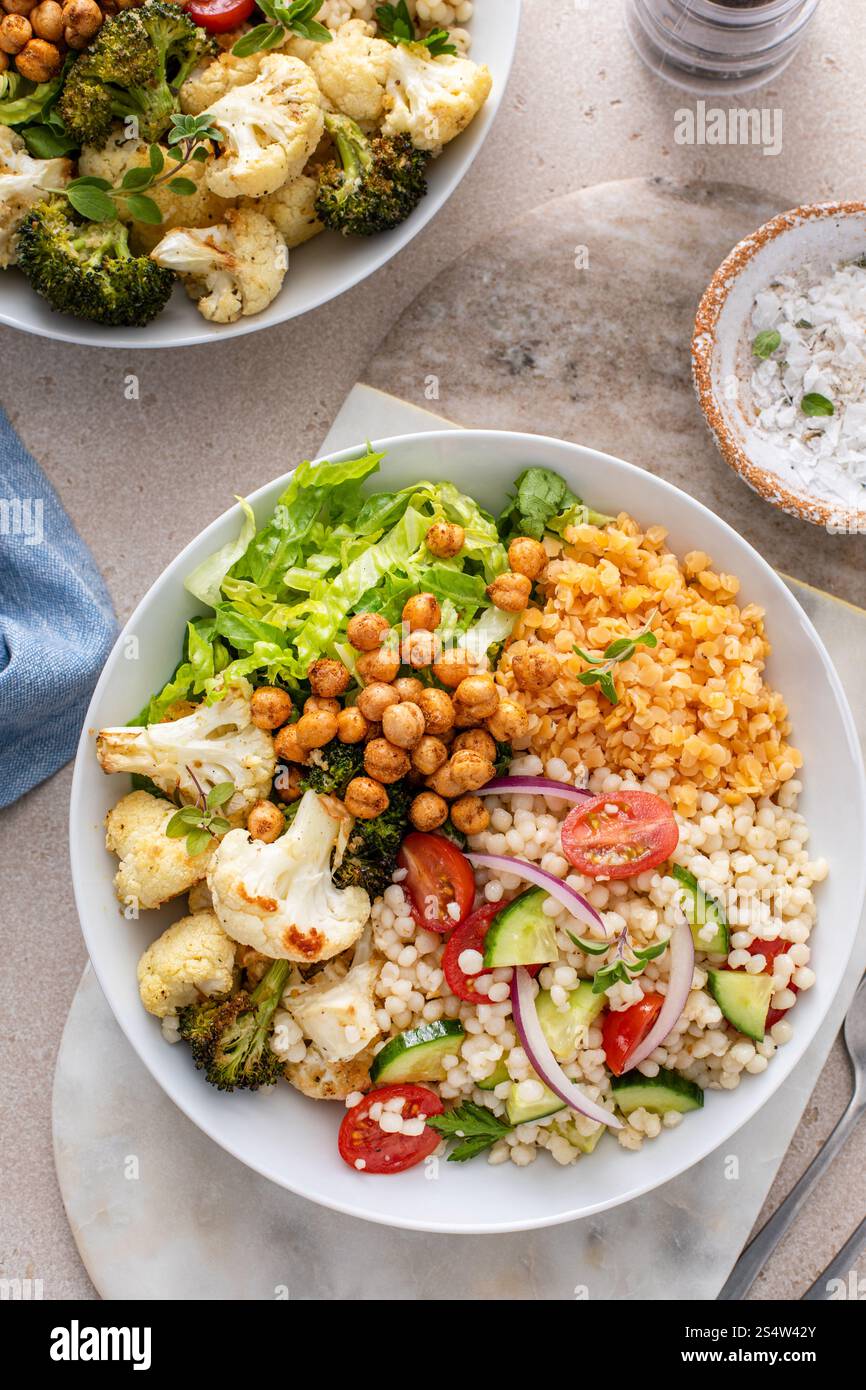 Vegan lunch bowl with lentils, roasted vegetables and chickpeas, pearl couscous salad with ...