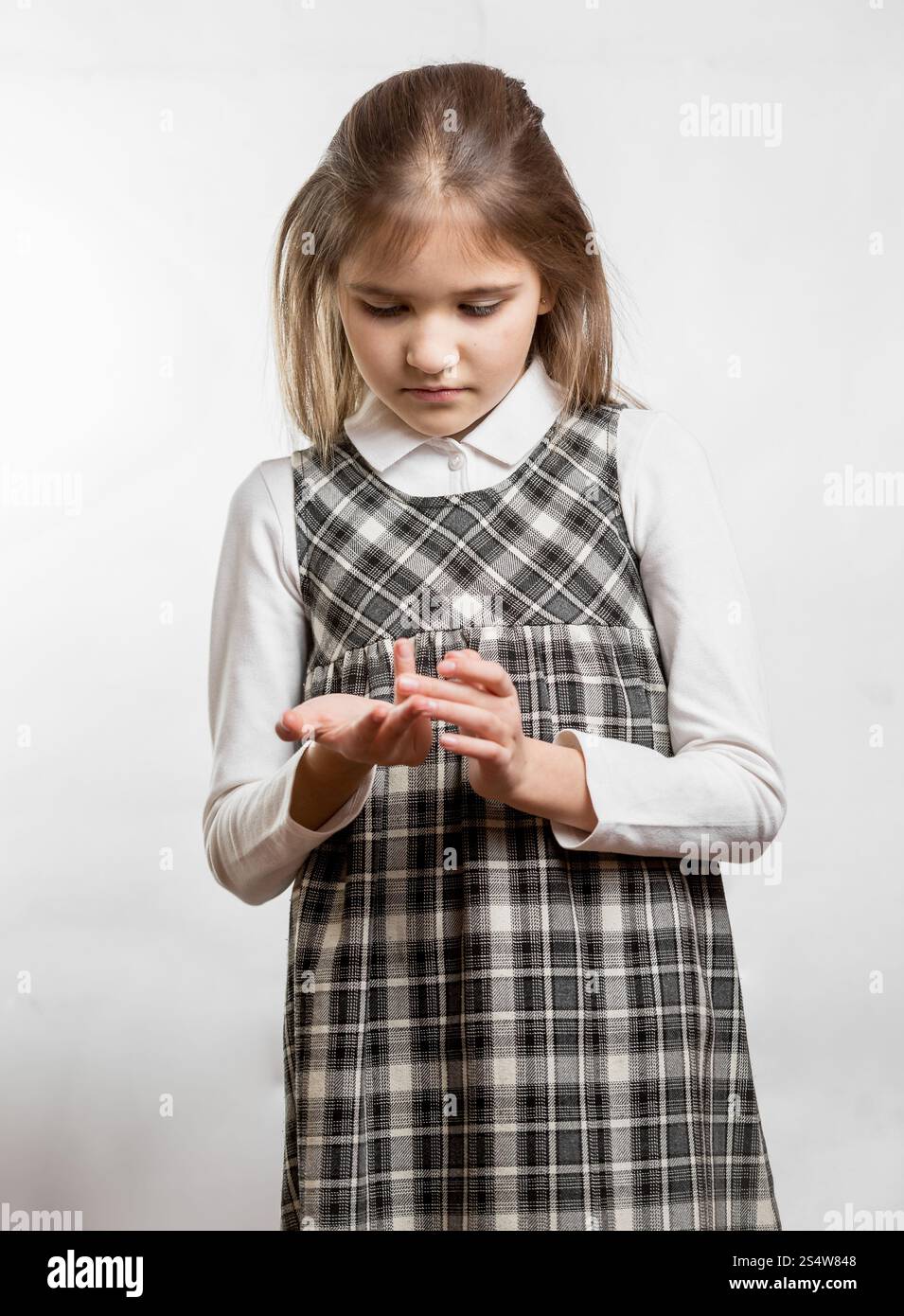 Portrait of cute little girl counting fingers against white background ...