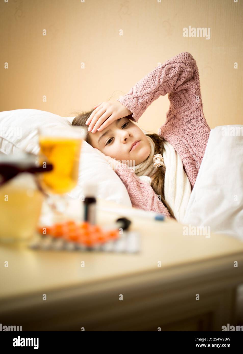 Closeup photo of sick girl lying in bed next to table table with ...