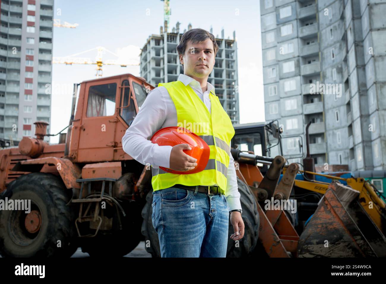 Portrait of construction inspector posing next to excavator on building ...