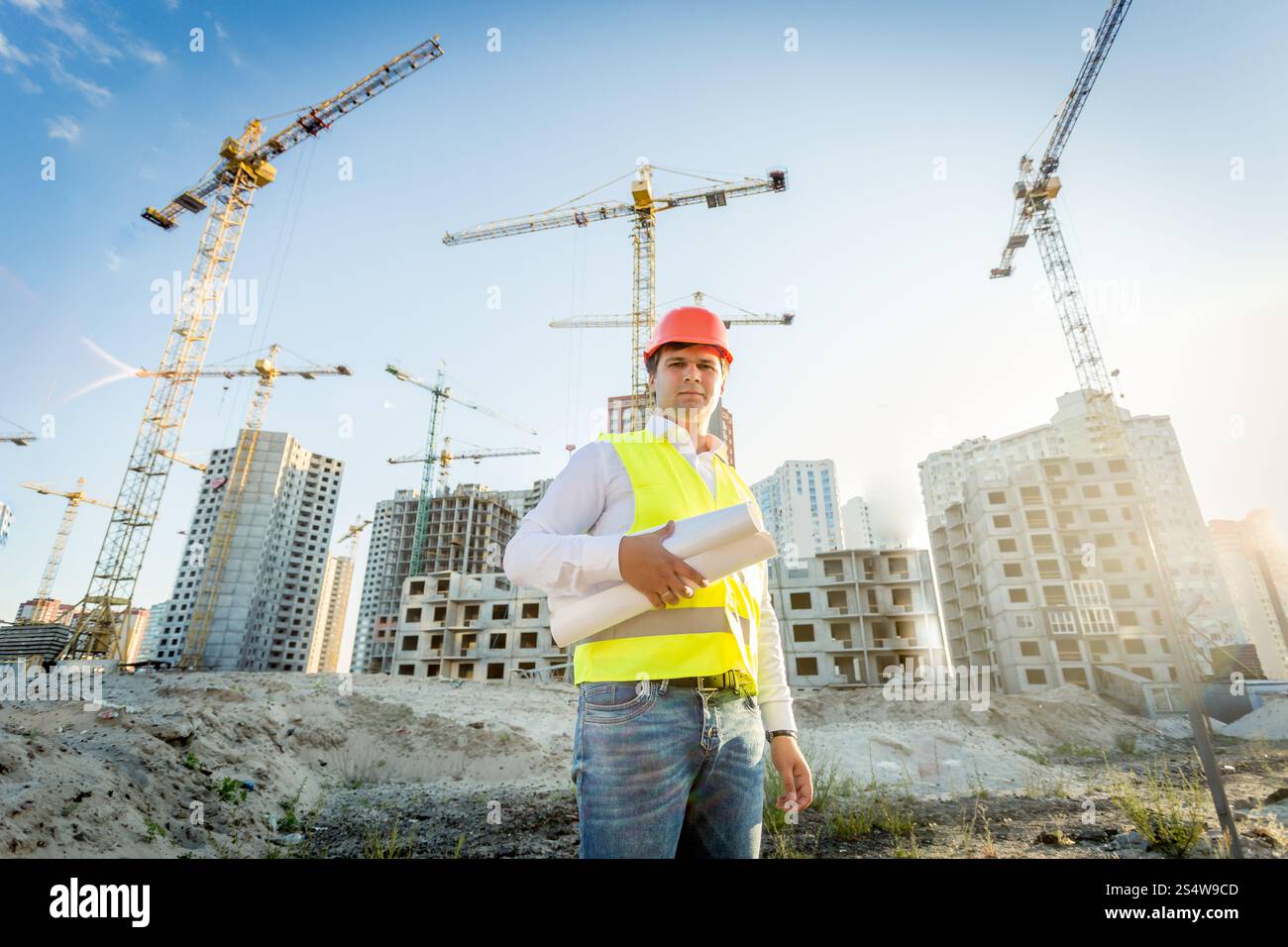 Portrait of construction inspector posing with blueprints on building ...