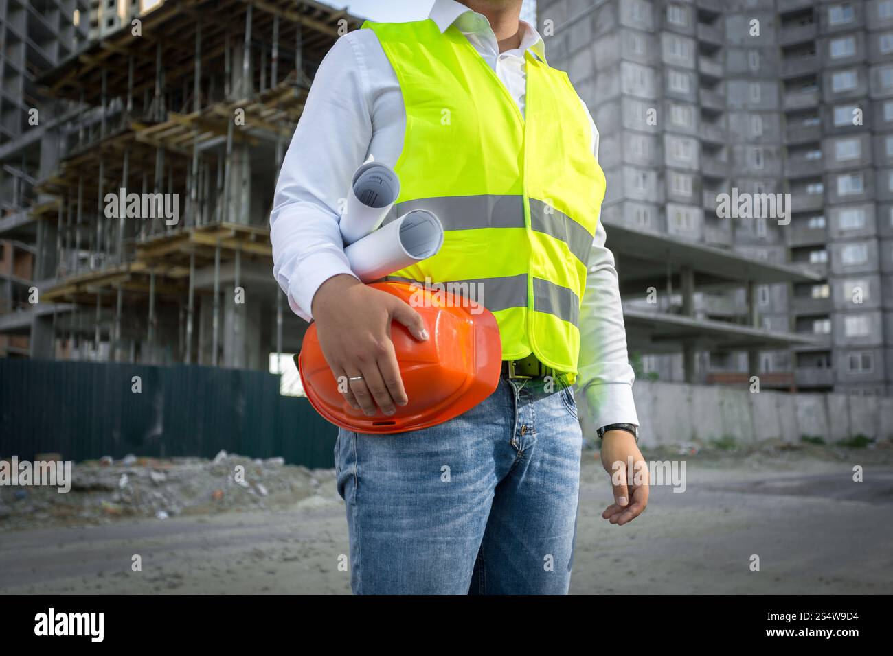 Architect in yellow safety jacket posing with red helmet at ...
