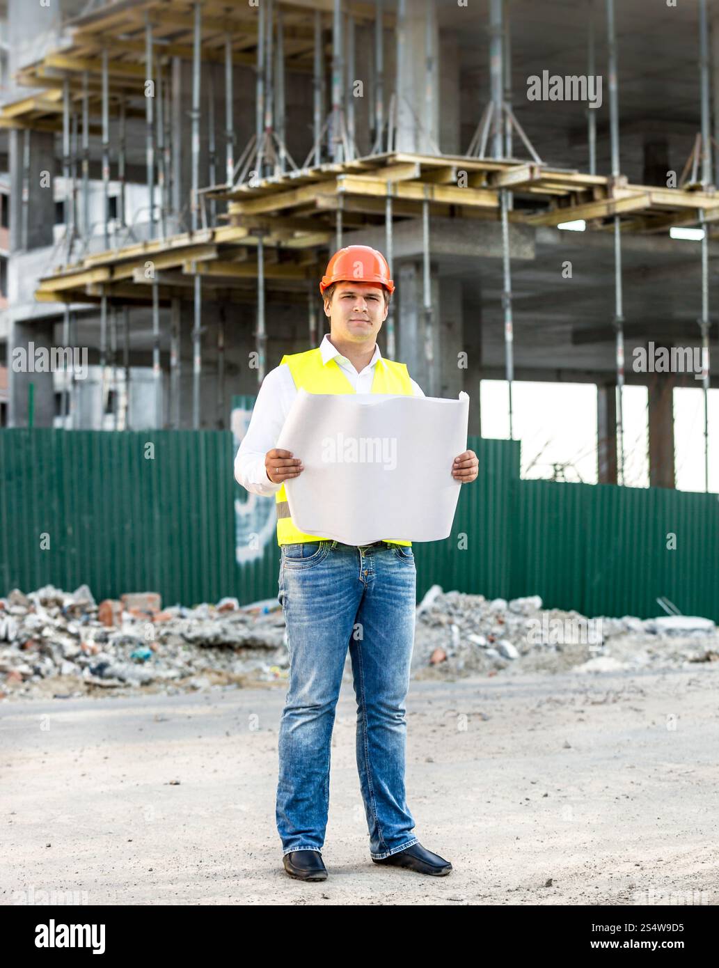 Young architect at work reading blueprints on building site Stock Photo ...
