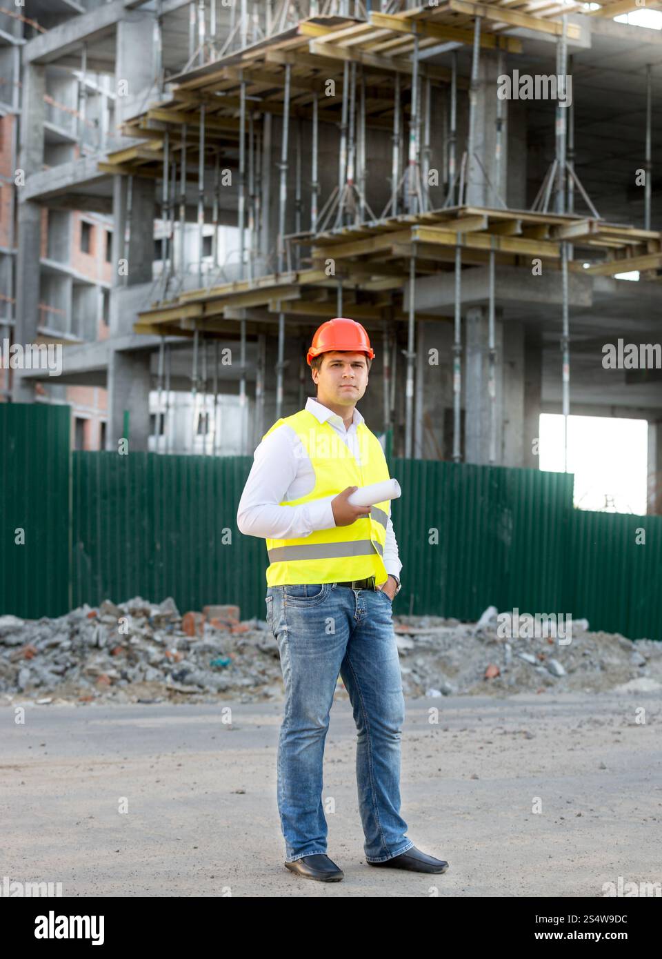 Foreman in jacket and helmet posing against building in scaffolding ...