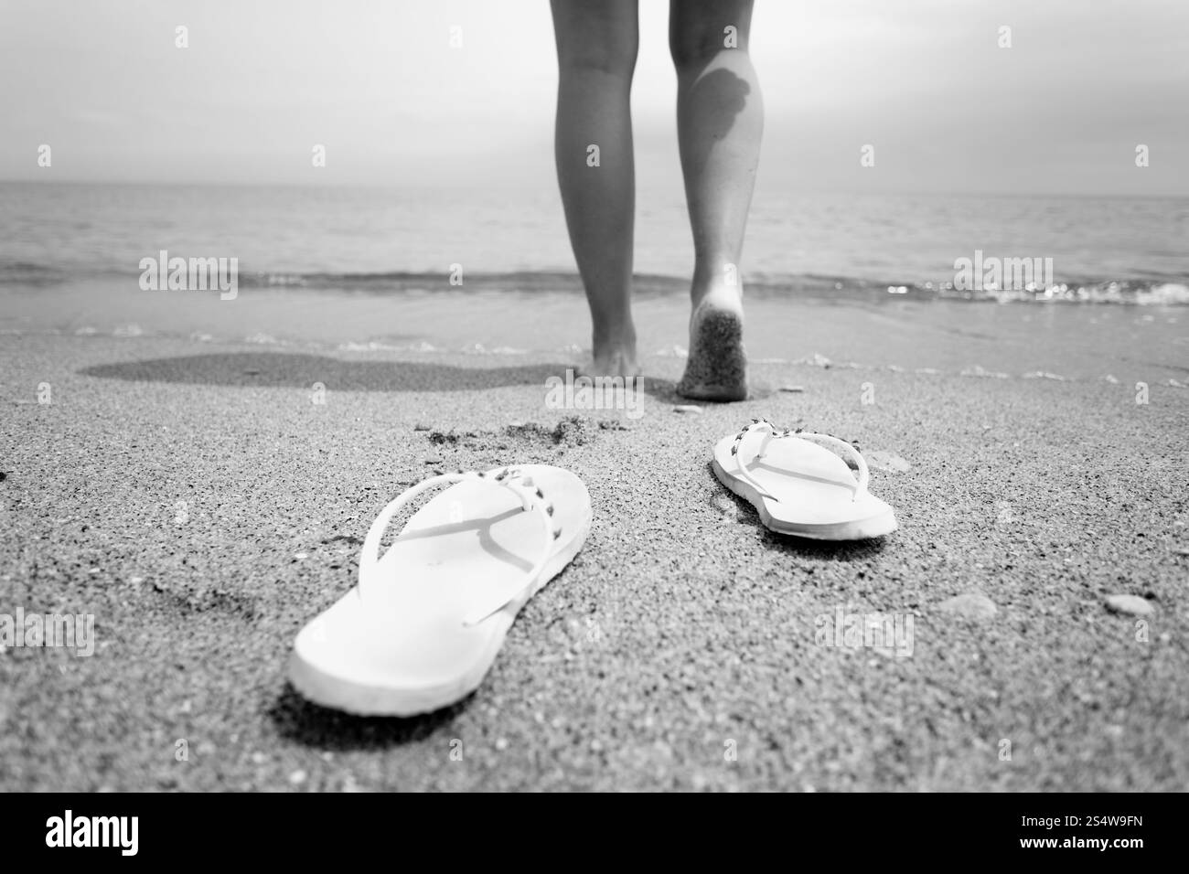 Black and white closeup photo of woman taking off flip flops and ...
