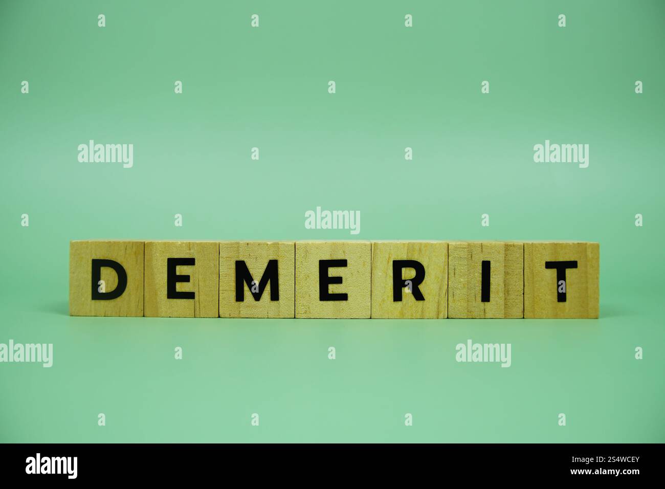 Demerit with wooden blocks alphabet letters on green background Stock ...