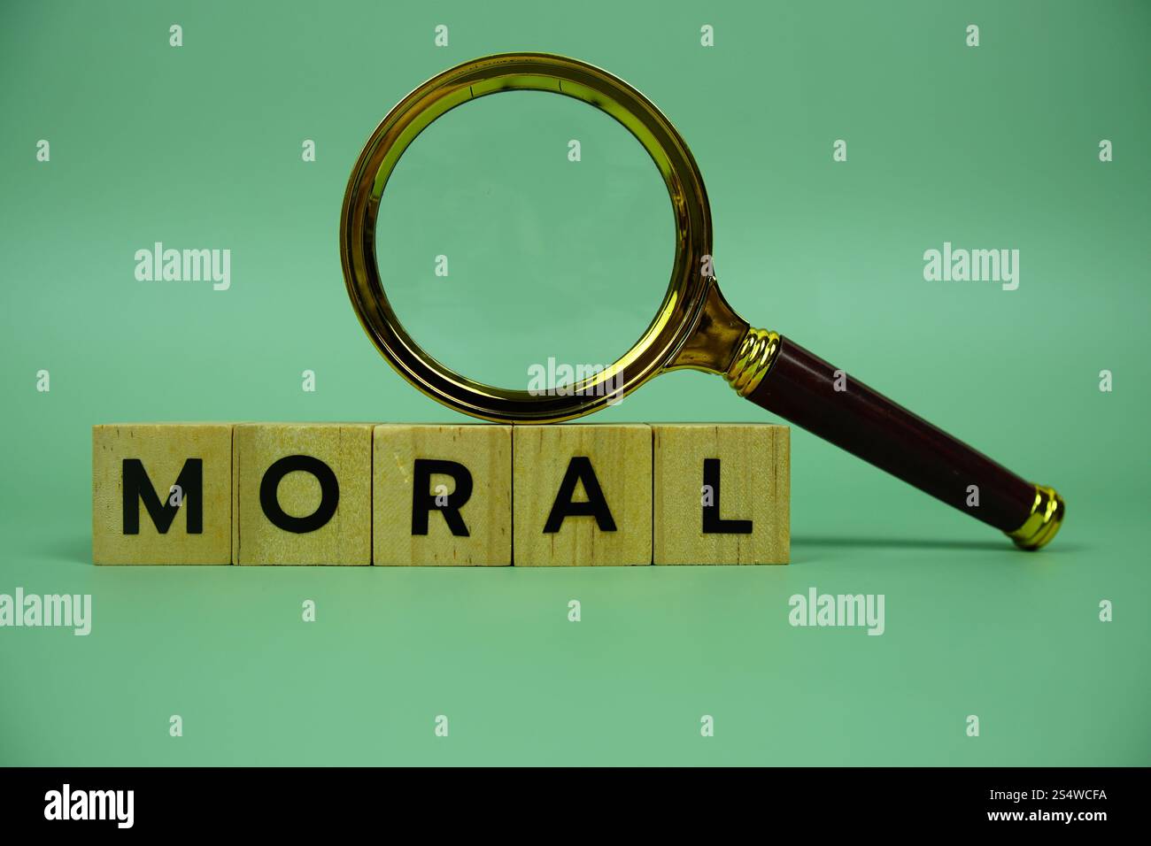 Moral with wooden blocks alphabet letters and magnifying glass on green ...