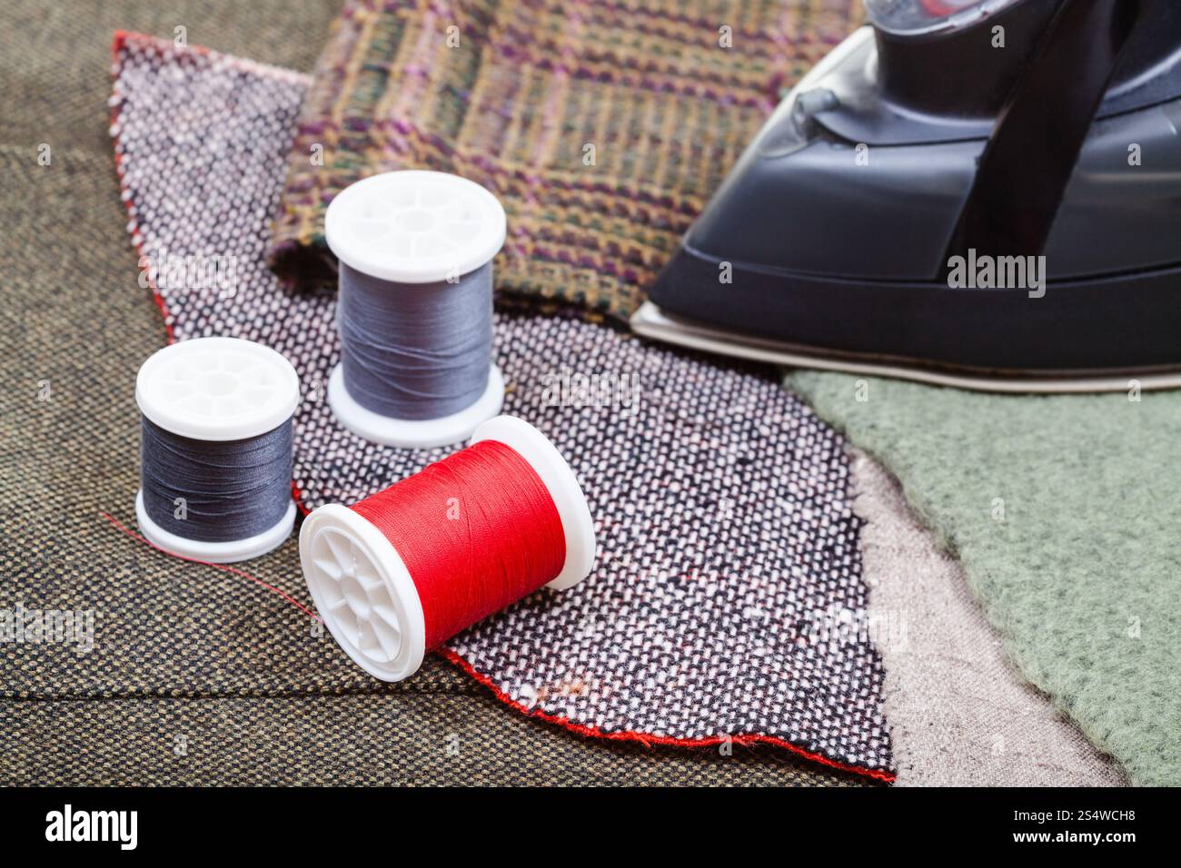 dressmaking still life - black clothing iron and thread spools on ...