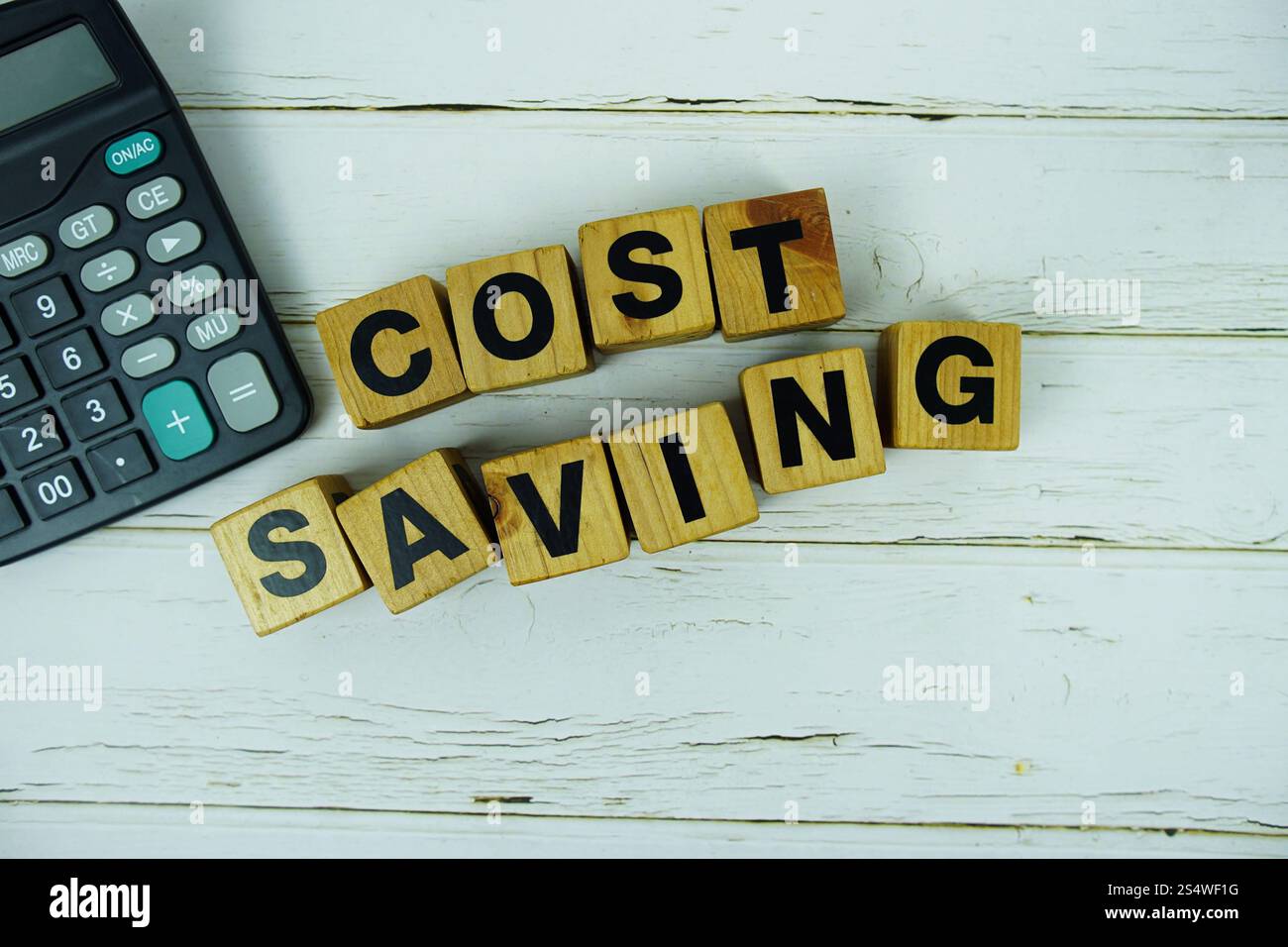 Cost Savings alphabet letters with calculator top view on wooden ...