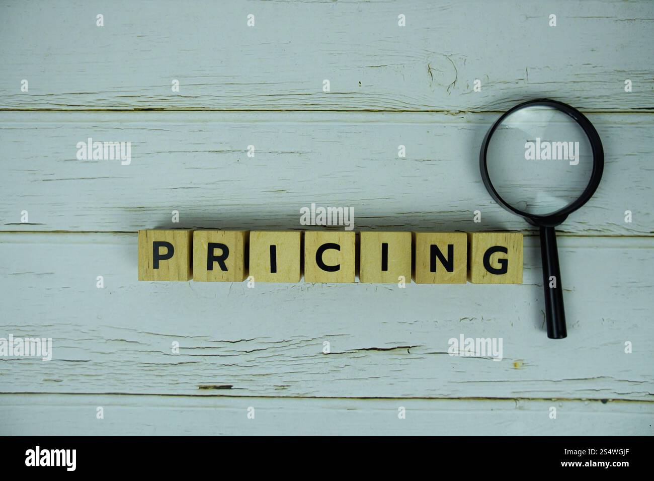Pricing with wooden blocks alphabet letters and magnifying glass on ...