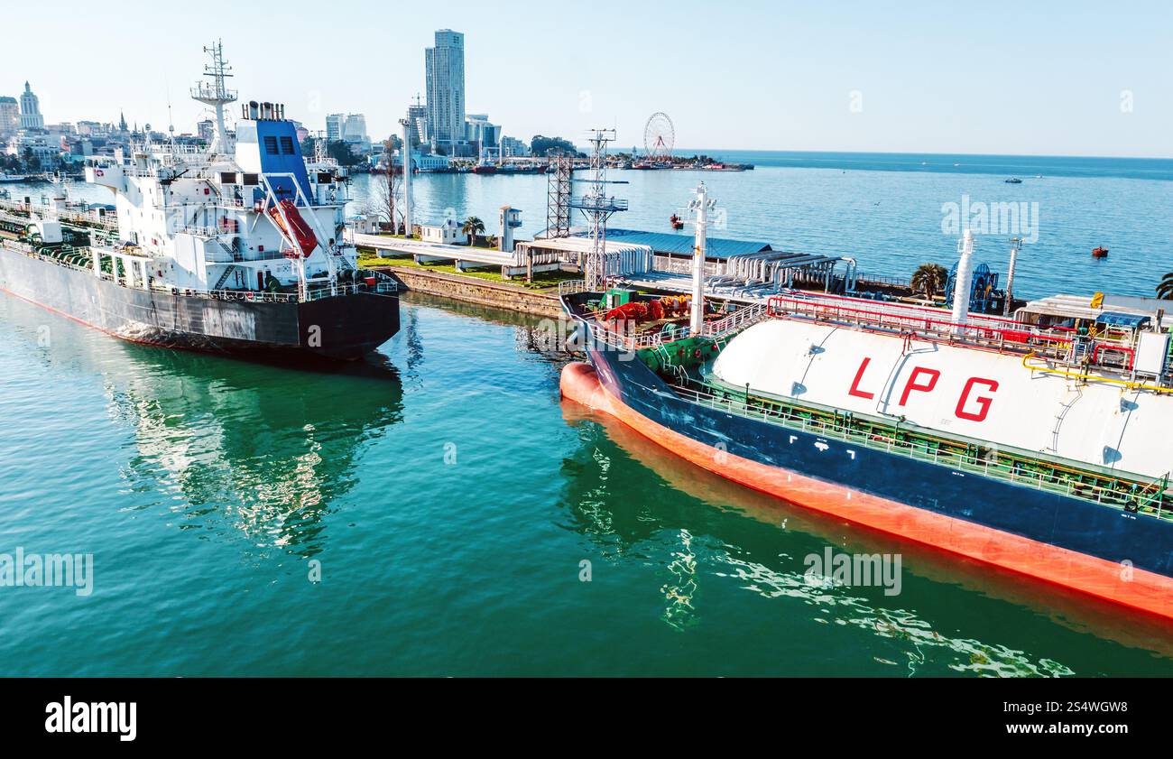 LPG tanker and cargo ship near industrial port with urban skyline in ...