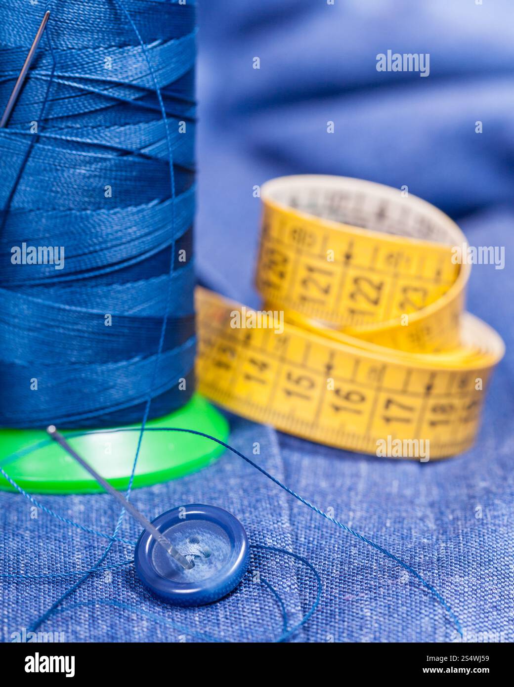 tailoring still life - thread bobbin with needle, button, measure tape ...