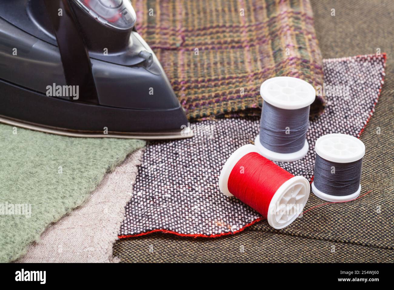 dressmaking still life - black clothing iron and thread spools on ...