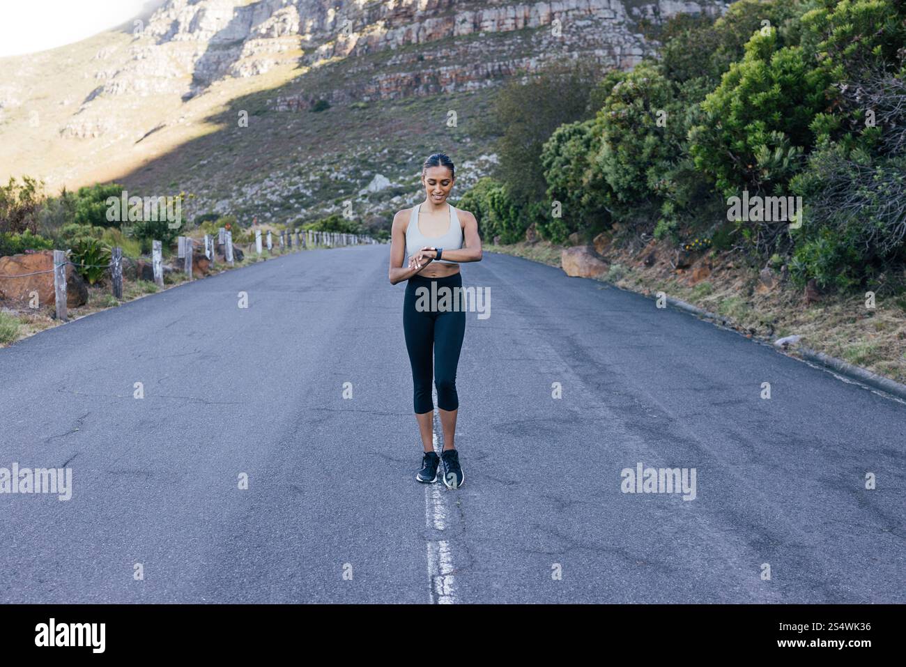 Full length of a smiling female walking on an abandoned road and ...