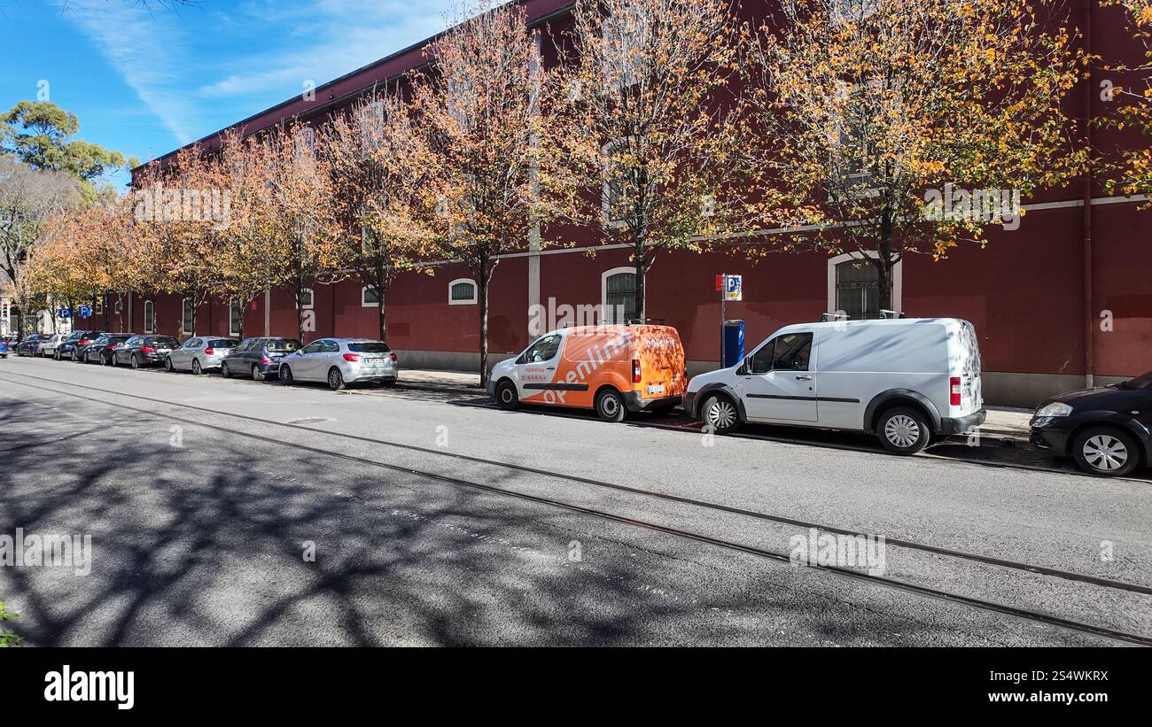 Lisbon street with a red building in the background and trees with ...
