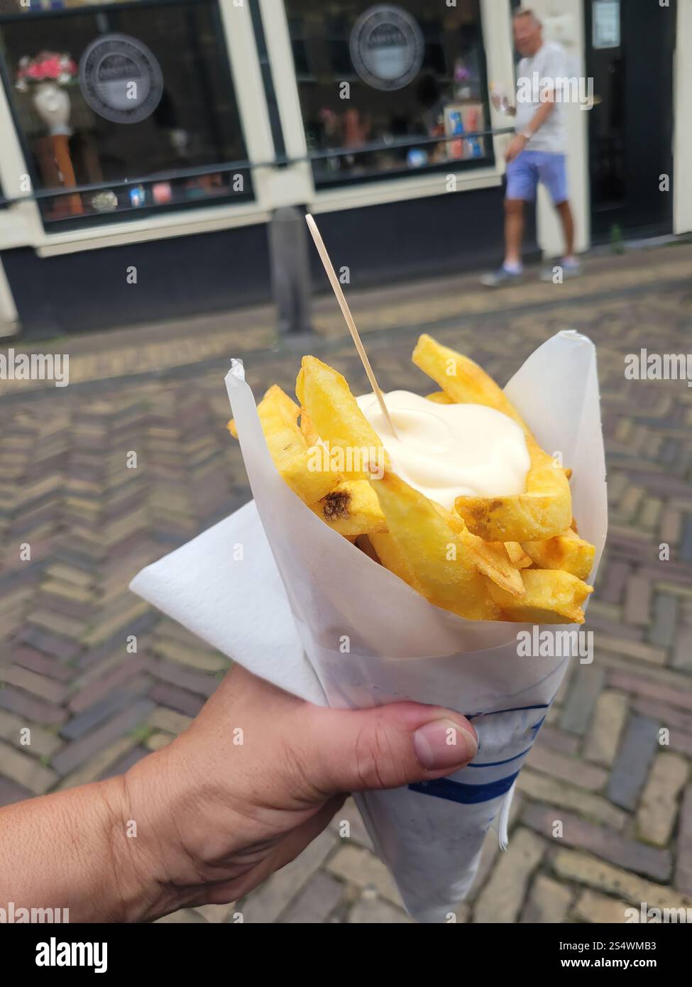 A portion of French fries in a bag, held by a human hand, in a city ...