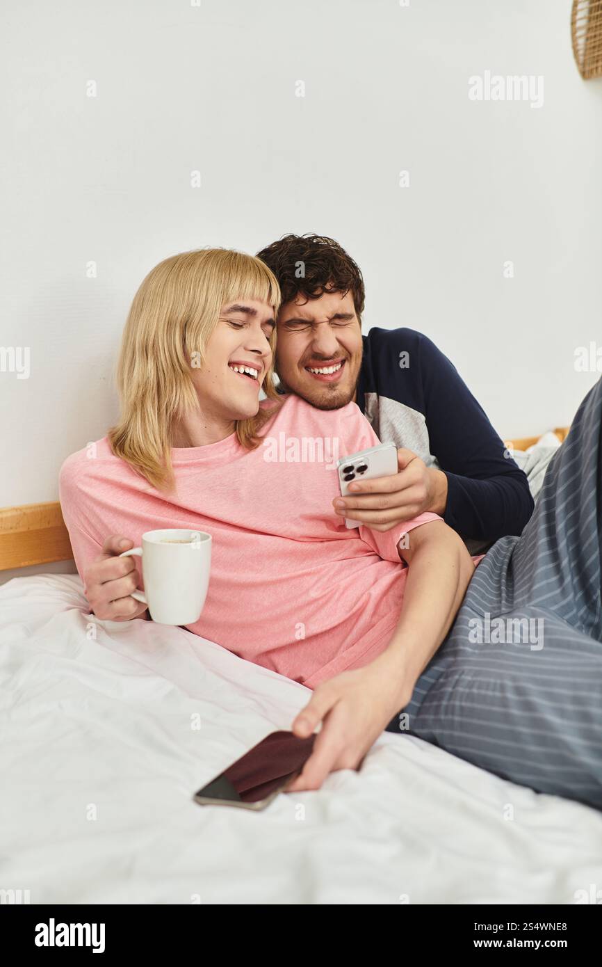 Two men cuddle on a bed, sharing smiles and laughter while enjoying ...