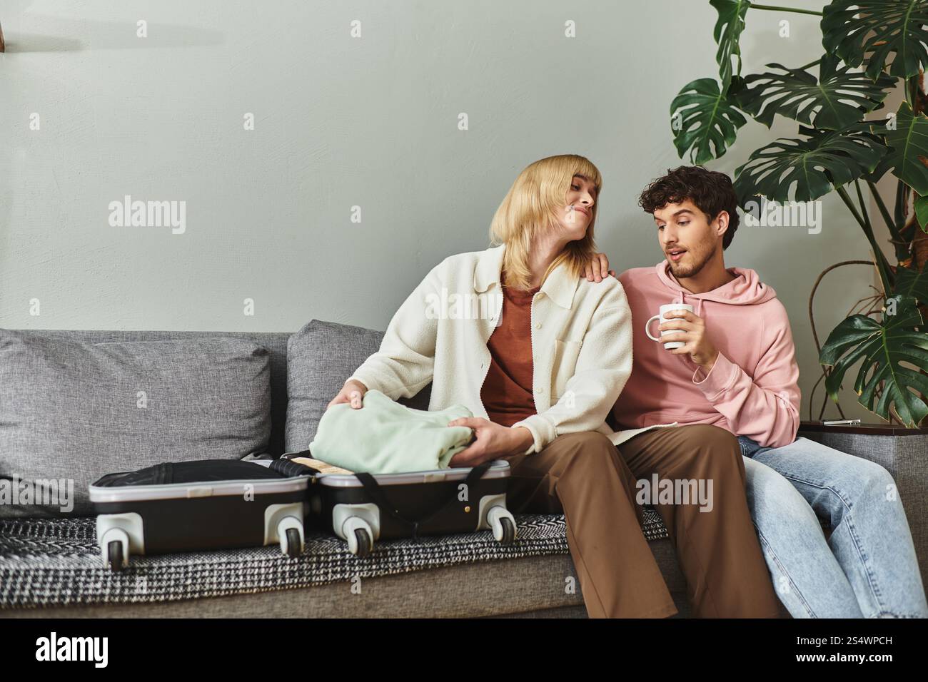 Two men relax on a couch, sharing laughter and warmth while preparing ...
